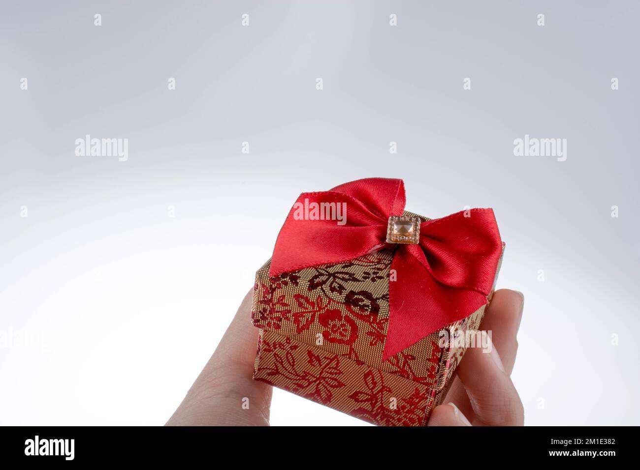 Hand holding a gift box with a red ribbon Stock Photo - Alamy