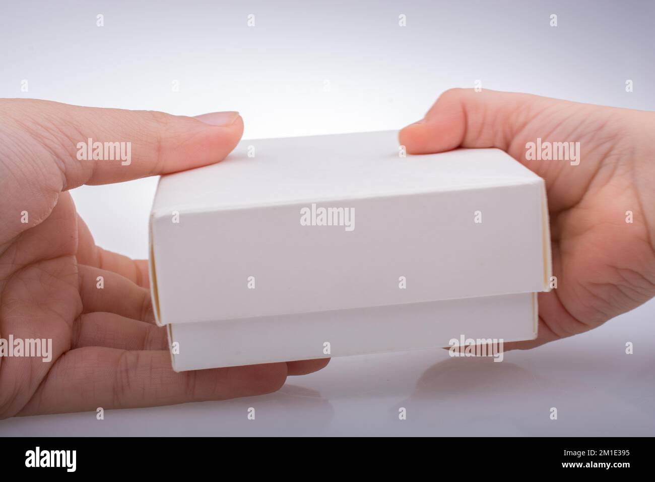 Hand giving a white gift box out Stock Photo - Alamy