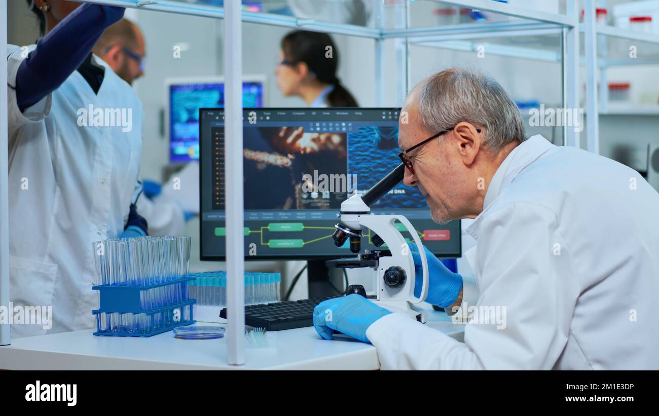 Medical research scientist conducting DNA experiments under microscope ...