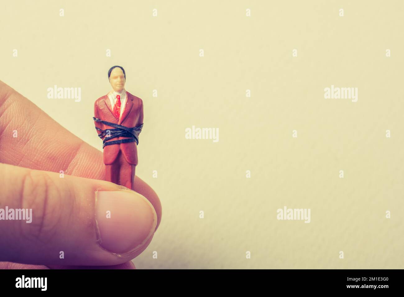 Hand holding tiny figurine of man model tied in a rope Stock Photo - Alamy