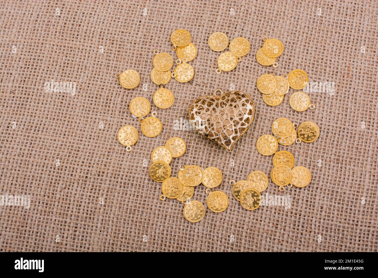 Fake gold coins around gold color heart Stock Photo - Alamy