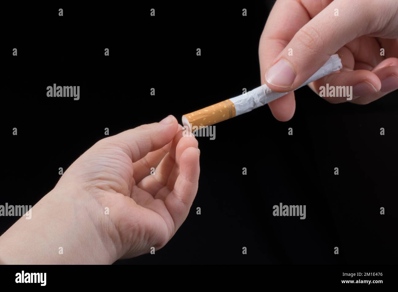 Hand is giving out cigarette on a black background Stock Photo - Alamy