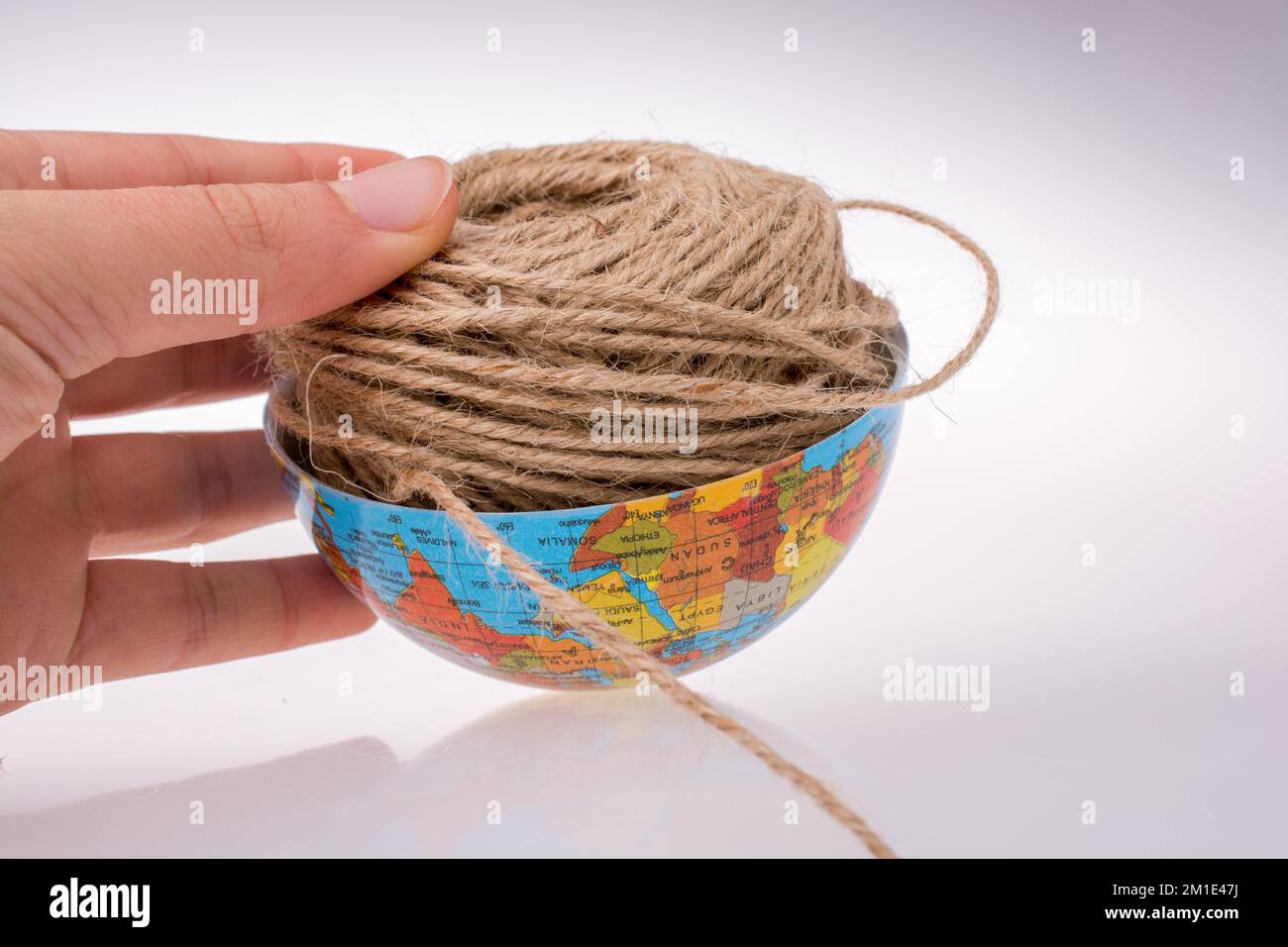 Spool of thread placed in a little colorful model globe Stock Photo - Alamy