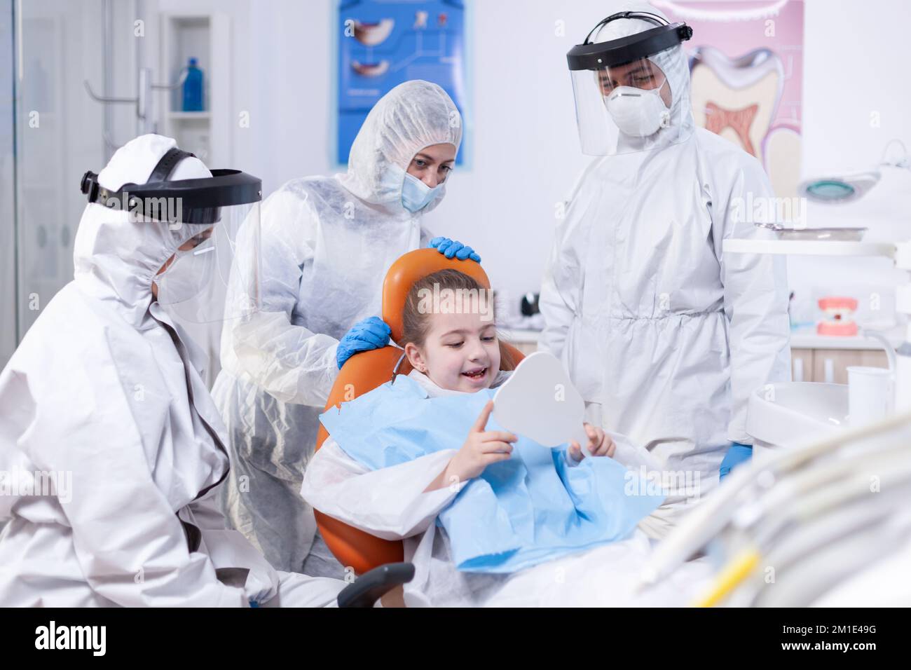 Excited kid dresse cover all holding mirror after stomatology procedure ...