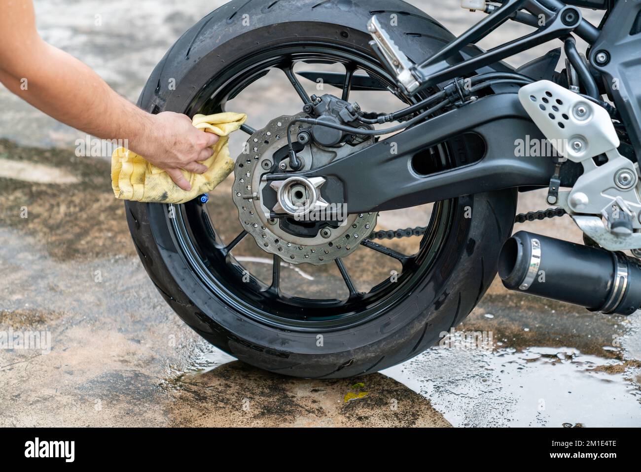 Hand of biker use yellow microfiber cloth washing a motorcycle wheel ...