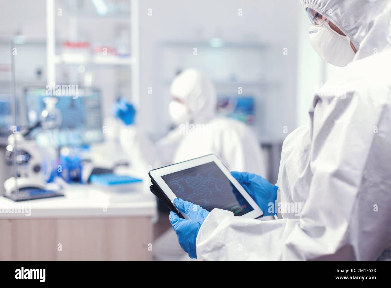 Back view of doctor in protection suit analyzing virus evolution ...