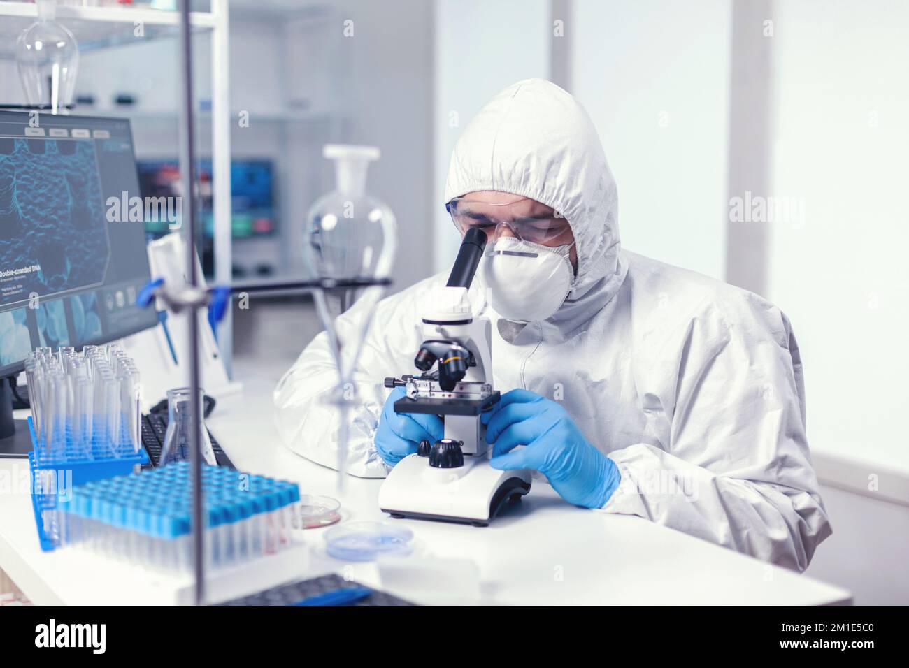Analyzing virus in microbiology lab using microscope wearing ppe suit ...