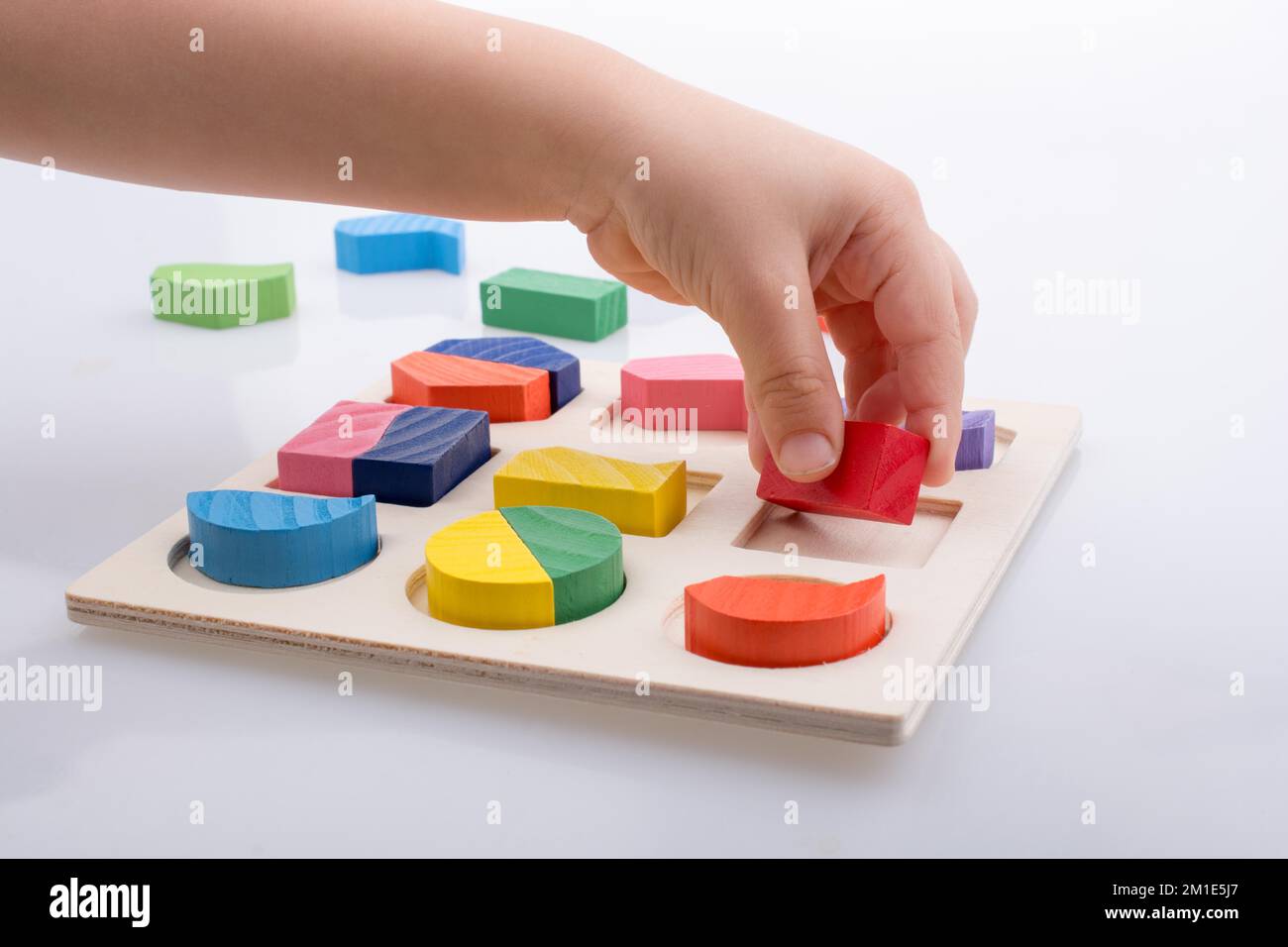 Colorful wooden pieces of a logic puzzle in hand Stock Photo - Alamy
