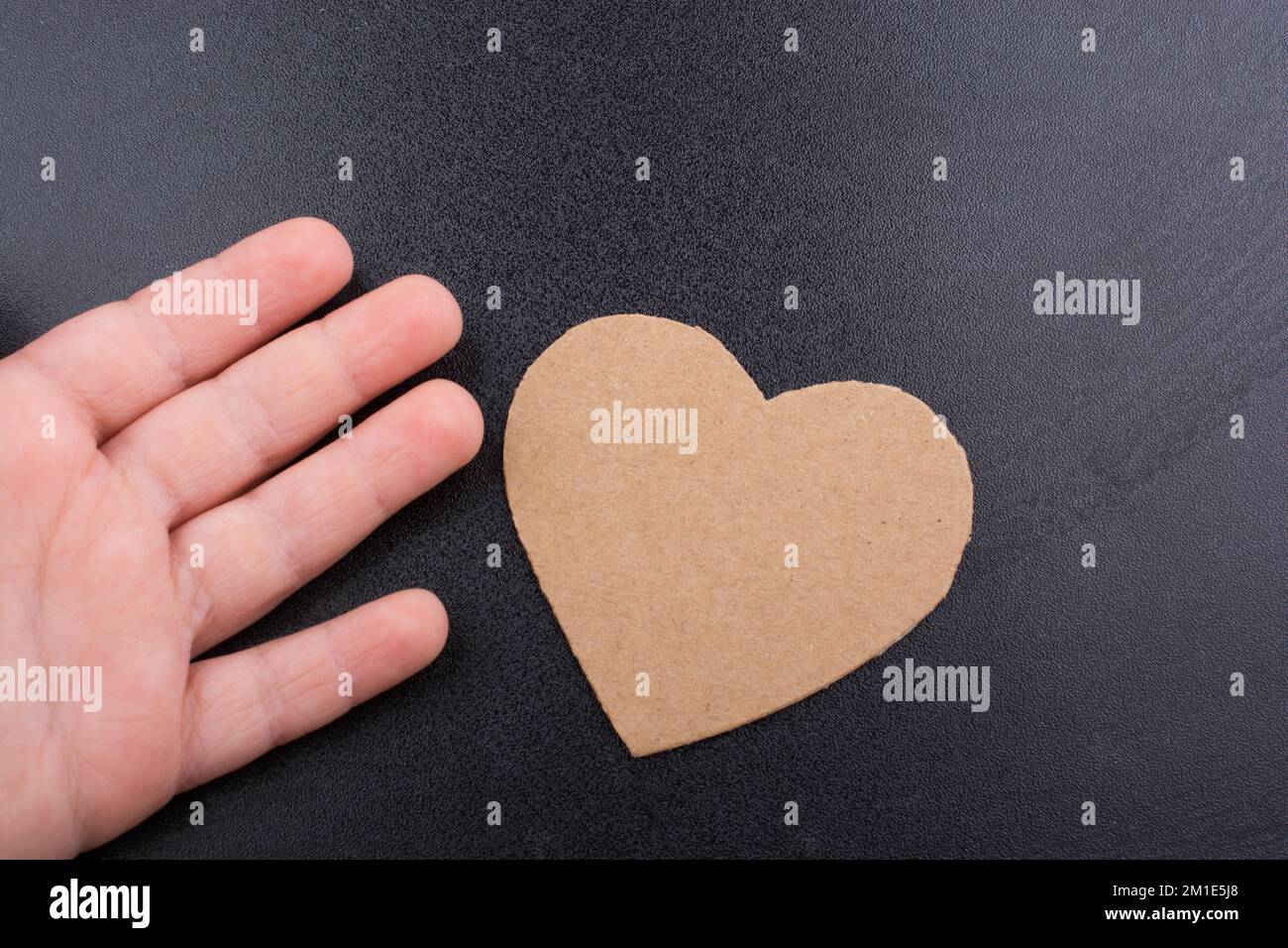 Hand is beside a heart shaped object on black Stock Photo - Alamy