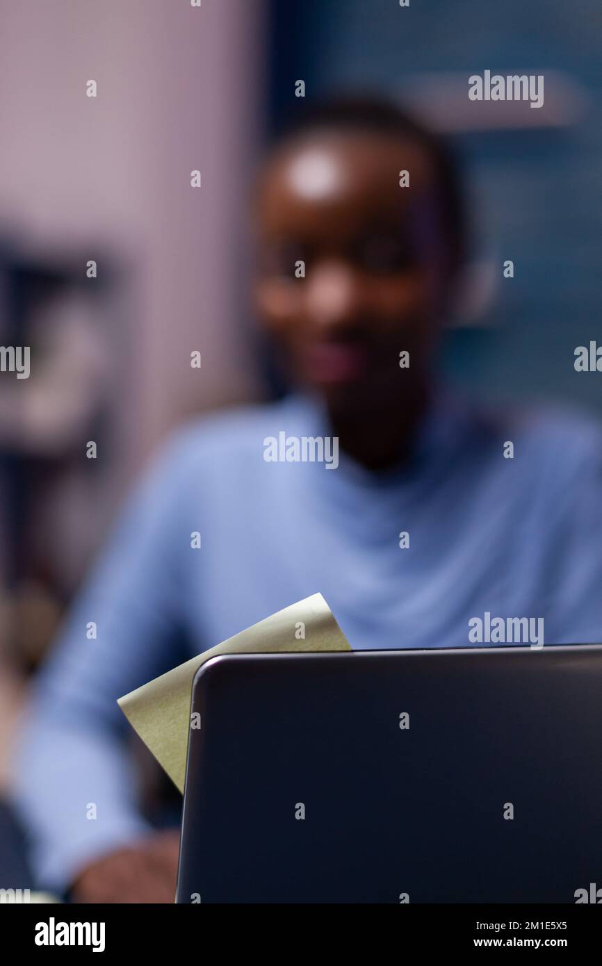 Sticky notes on laptop with african business woman blured in the ...