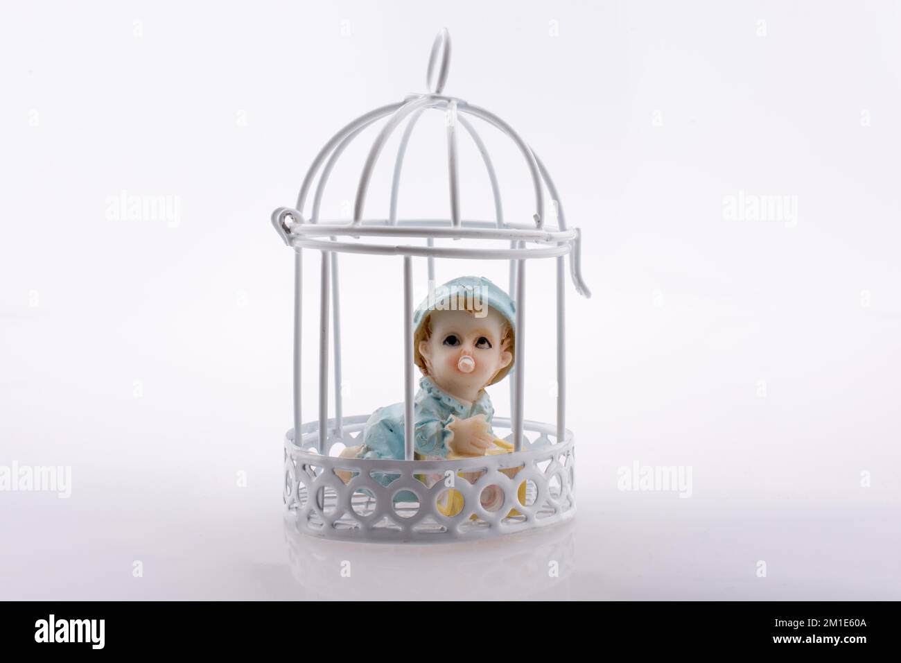 Little baby doll in cage on a white background Stock Photo - Alamy