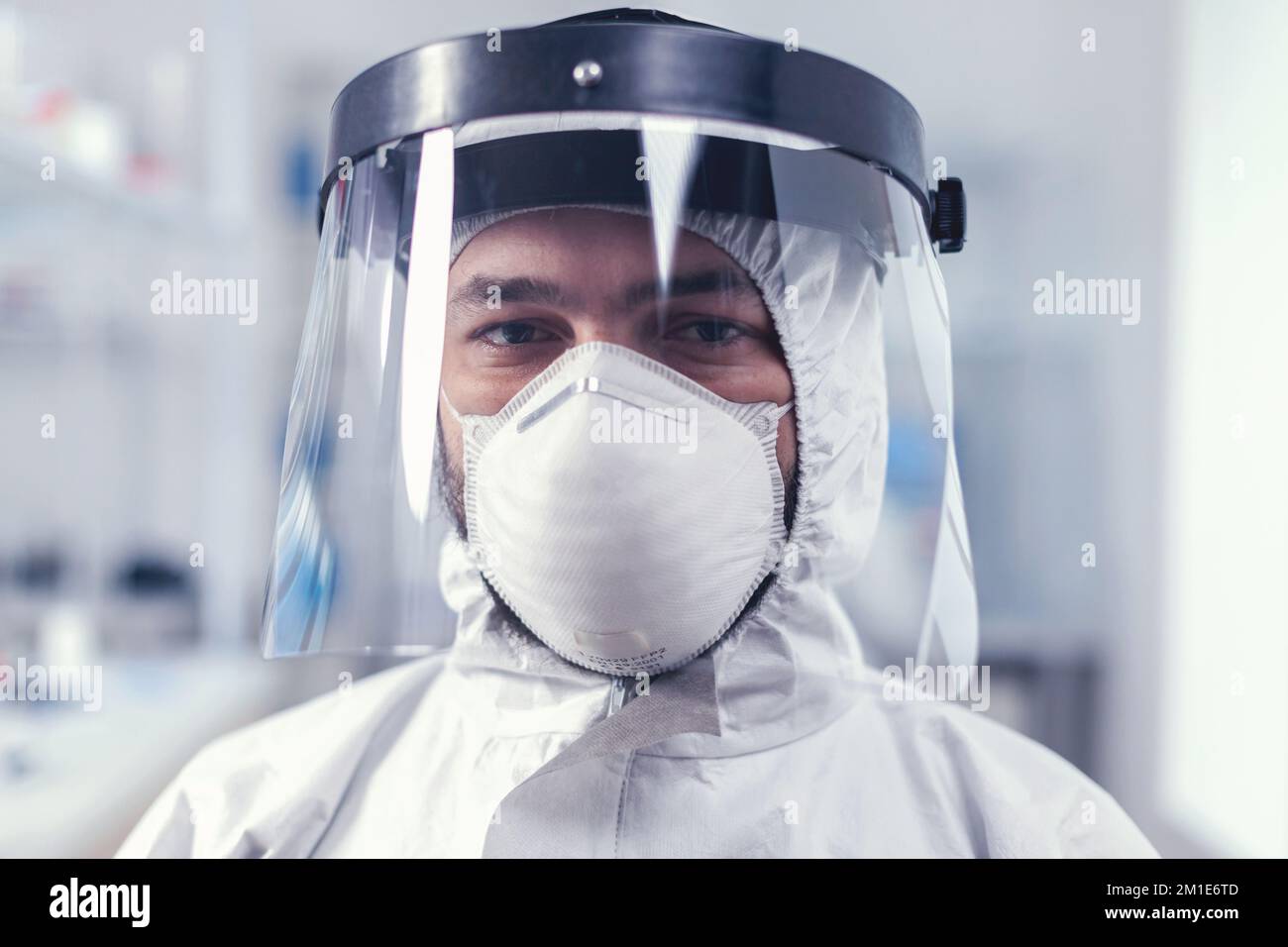Tired healthcare scientist loooking at camera wearing ppe suit with ...