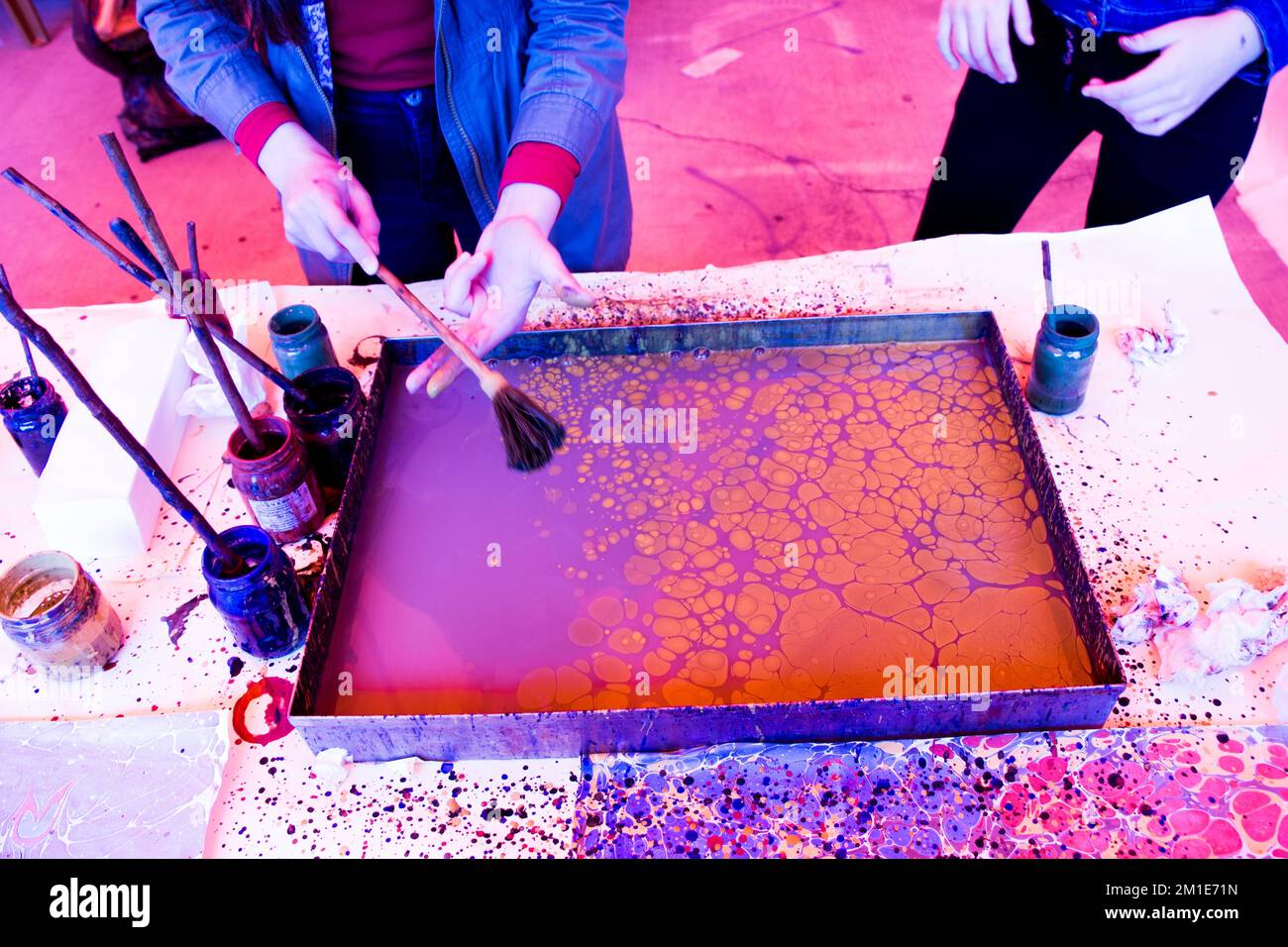 Hand splashing paint over water surface in marbling Stock Photo - Alamy
