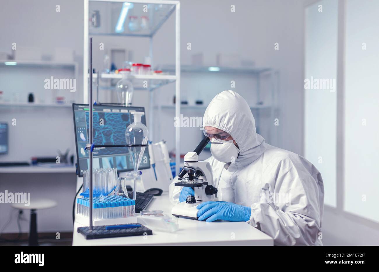 Scientist studying new virus in laborator using microscope dressed in ...