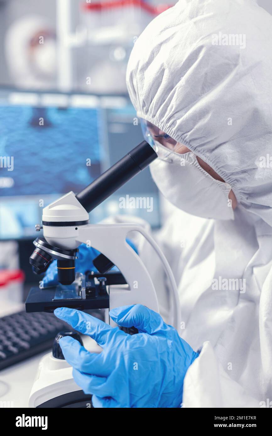 Medical scientist analysing sample on glass slide looking through ...