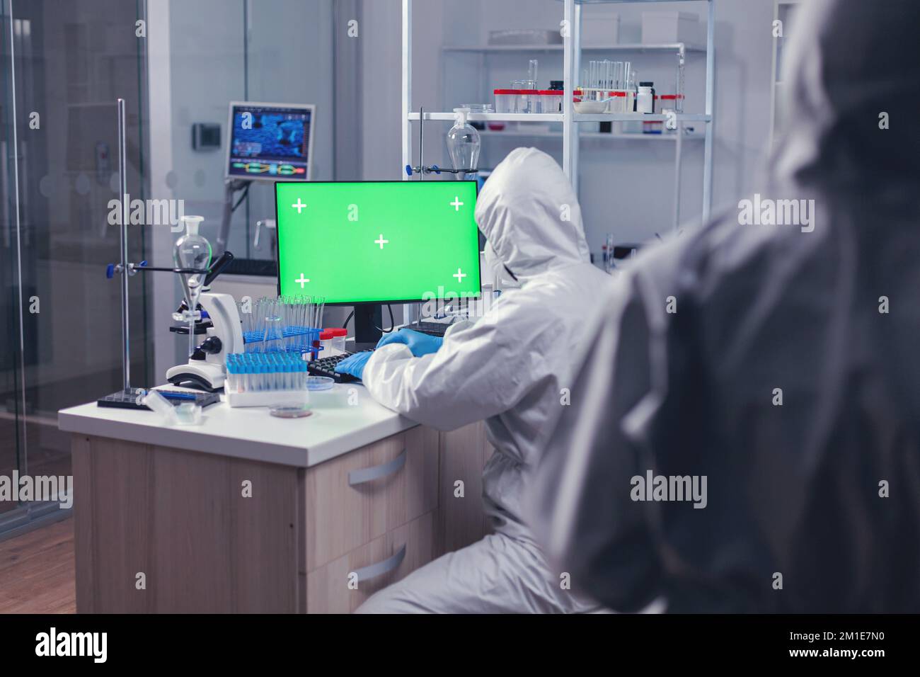 Scientist dressed in ppe suit working on computer with green screen ...