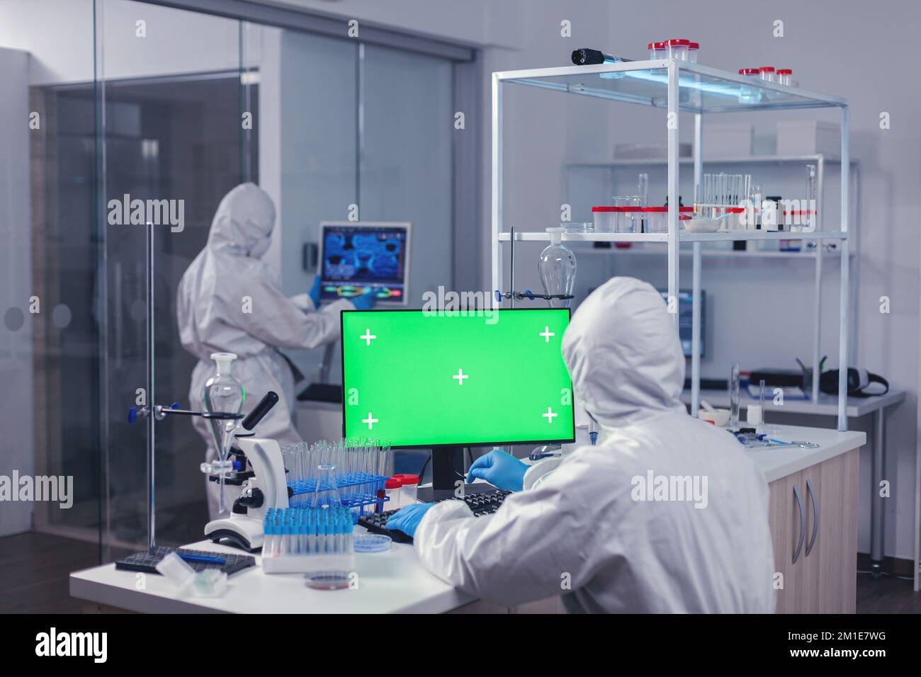 Computer with green screen in lab and medical staff dressed in ppe suit ...