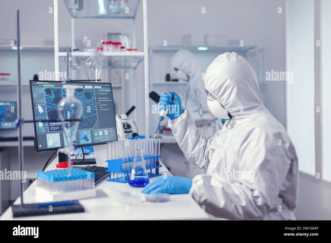 Concentrated scientist using micropipette with a test tube and coworker ...