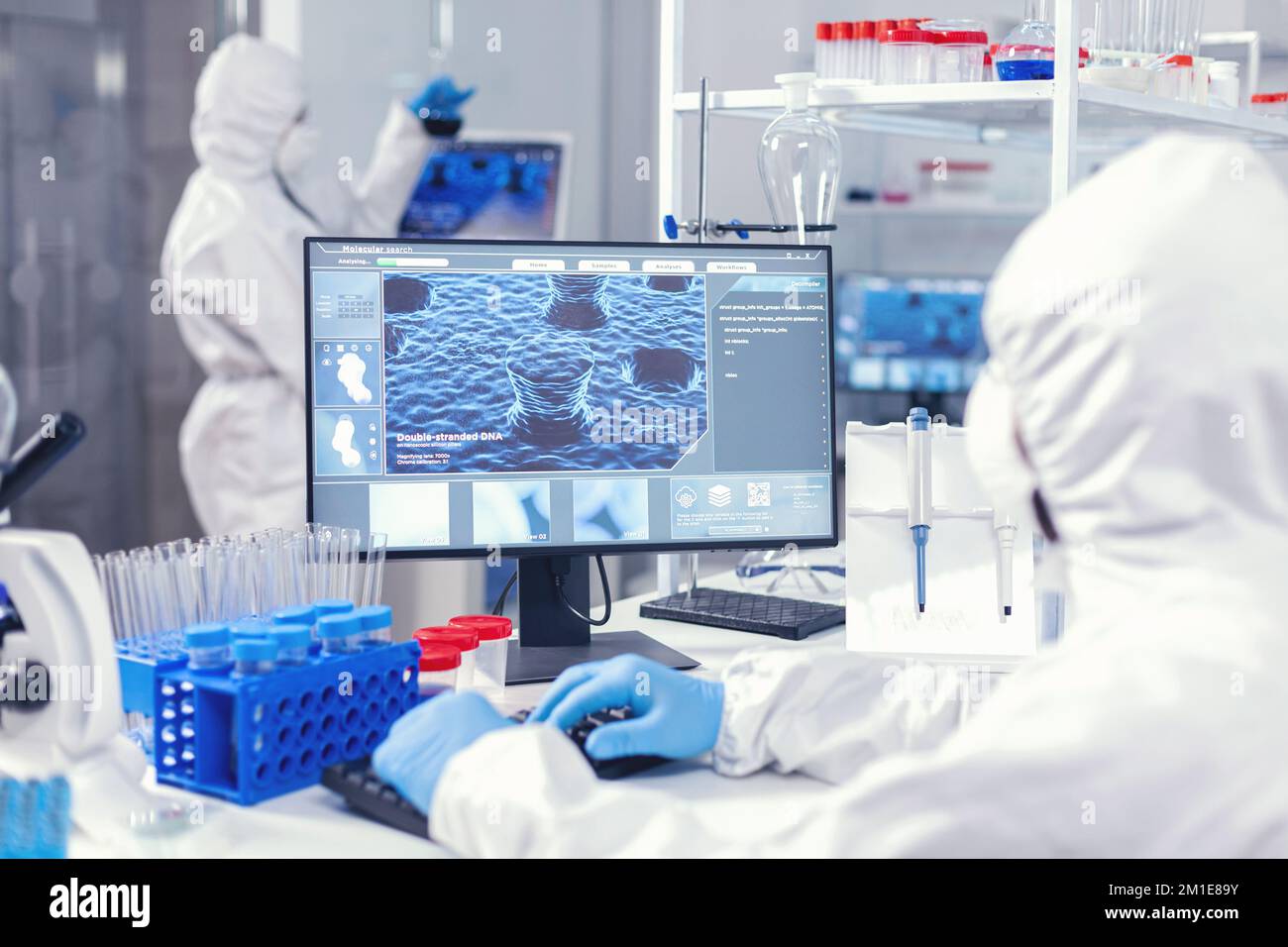 Scientist in modern lab working on computer during coronavirus dressed ...
