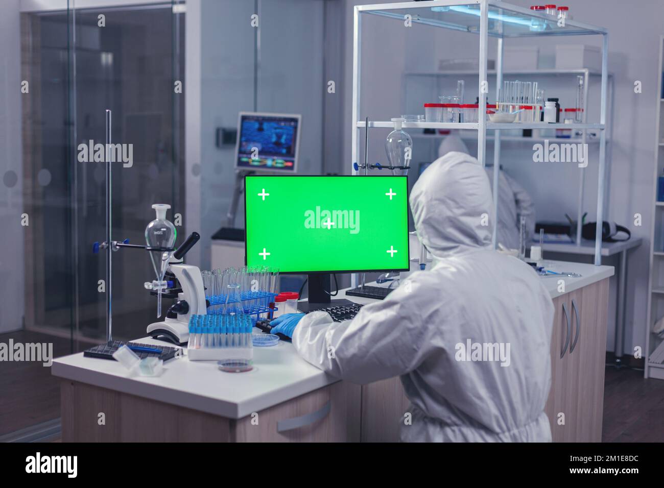 Medical scientist working on computer with green screen sitting at his ...