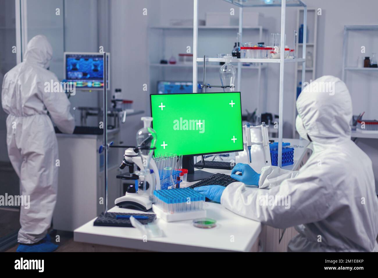 Laboratory technician in medicine lab uses computer with green screen ...