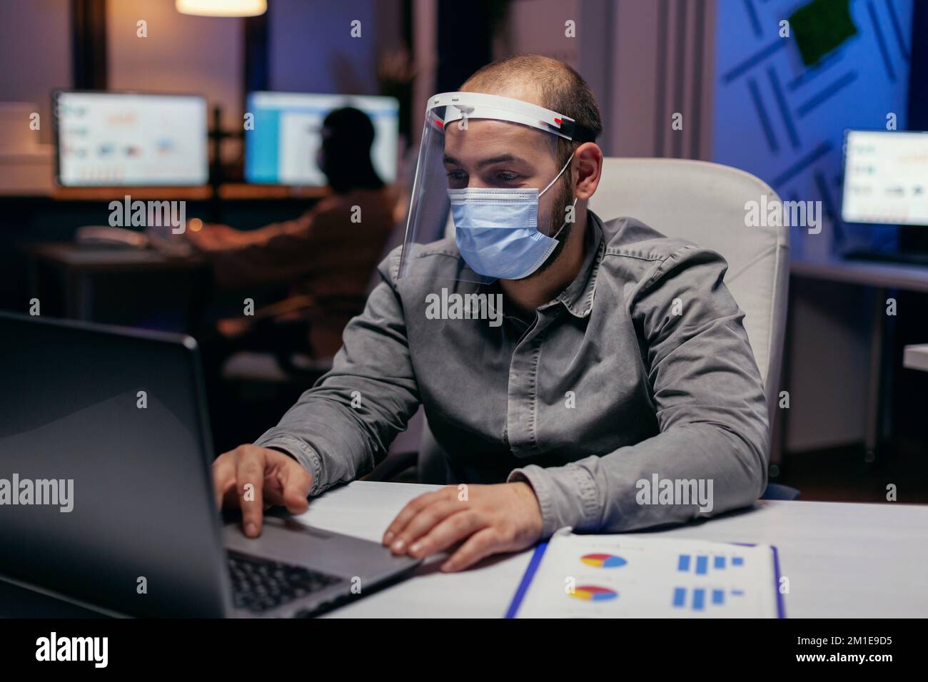 Entrepreneur analyzing business reports on laptop wearing visor ...