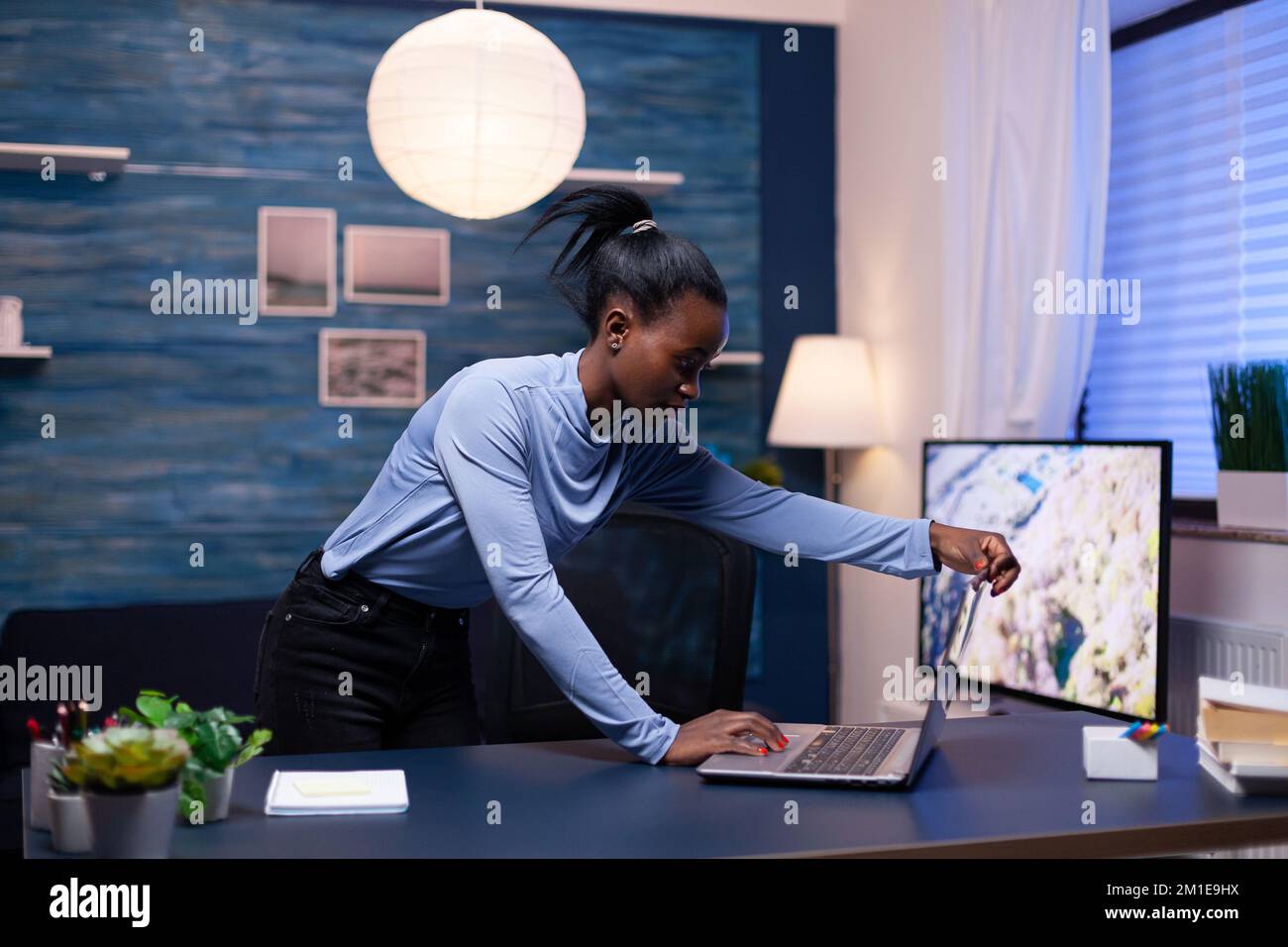 African entrepreneur working from home late at night using laptop to ...