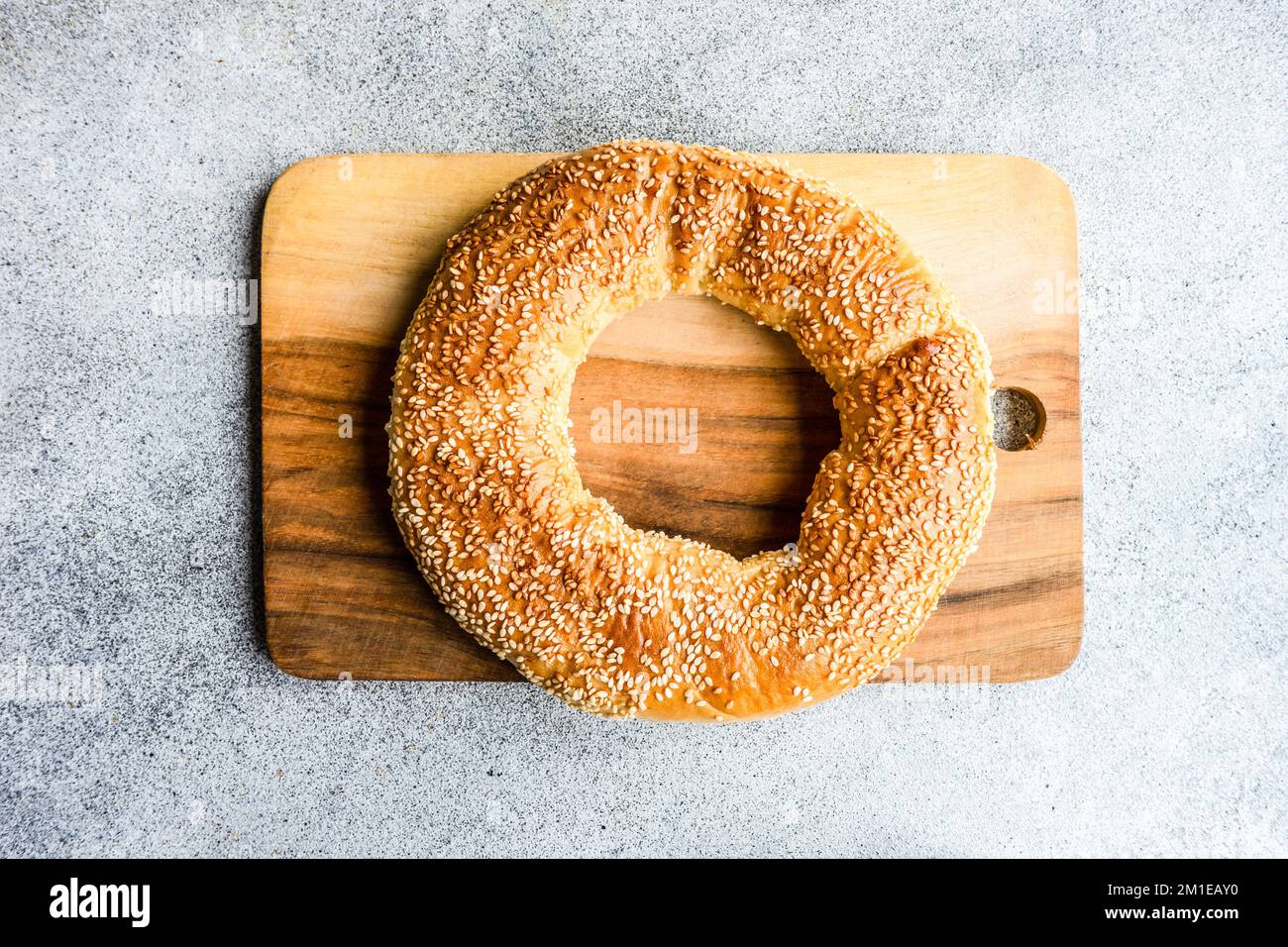 Overhead view of a Greek sesame bread ring (koulouria) on a chopping ...