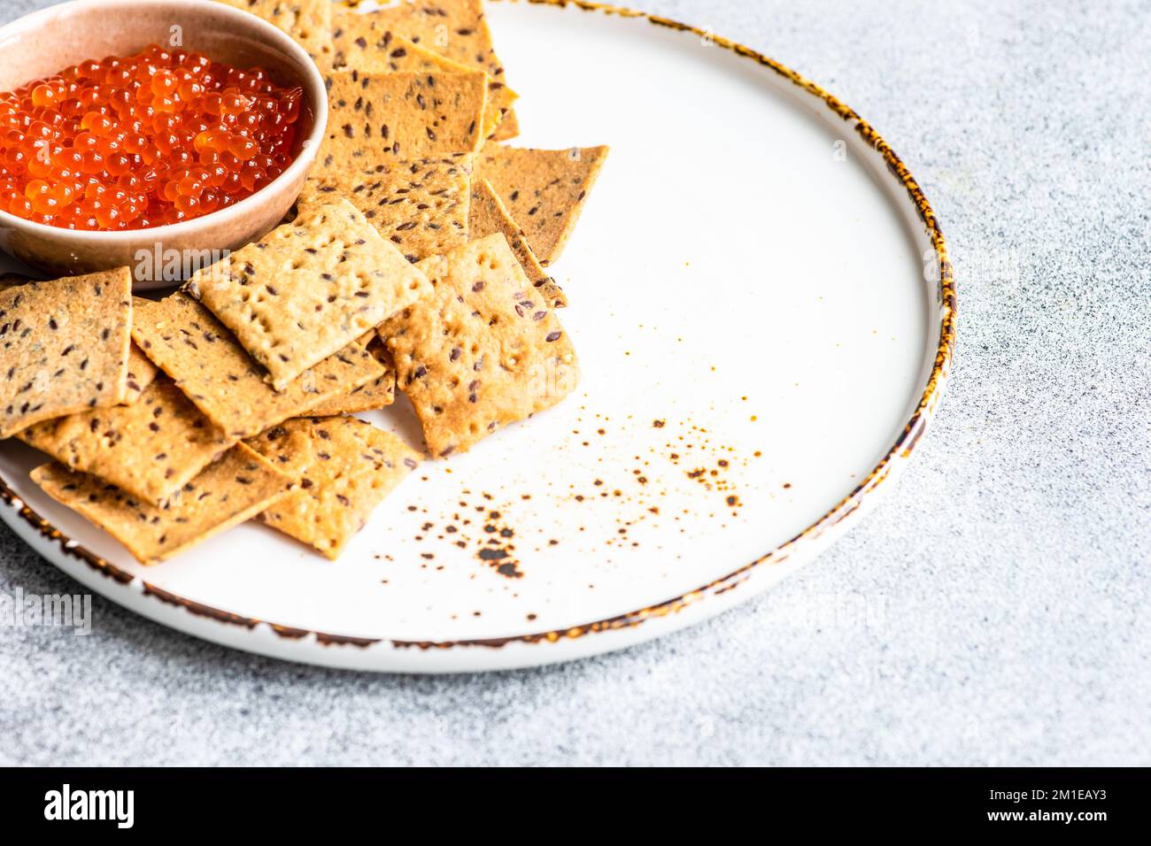 Bowl of red trout fish caviar with flax and sesame seed crackers Stock ...