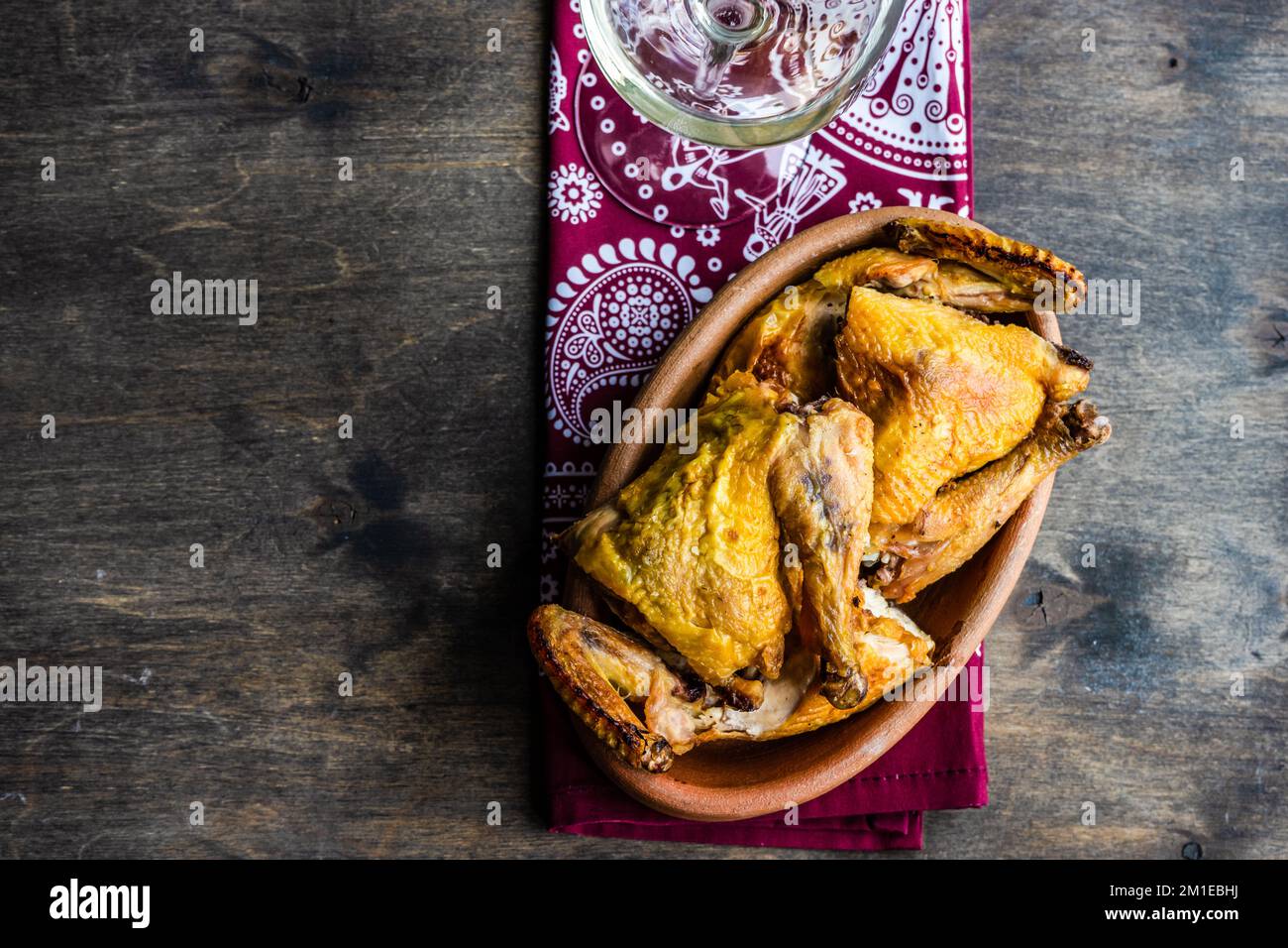 Dish with chicken tabaka and a glass of white wine on a table with a ...