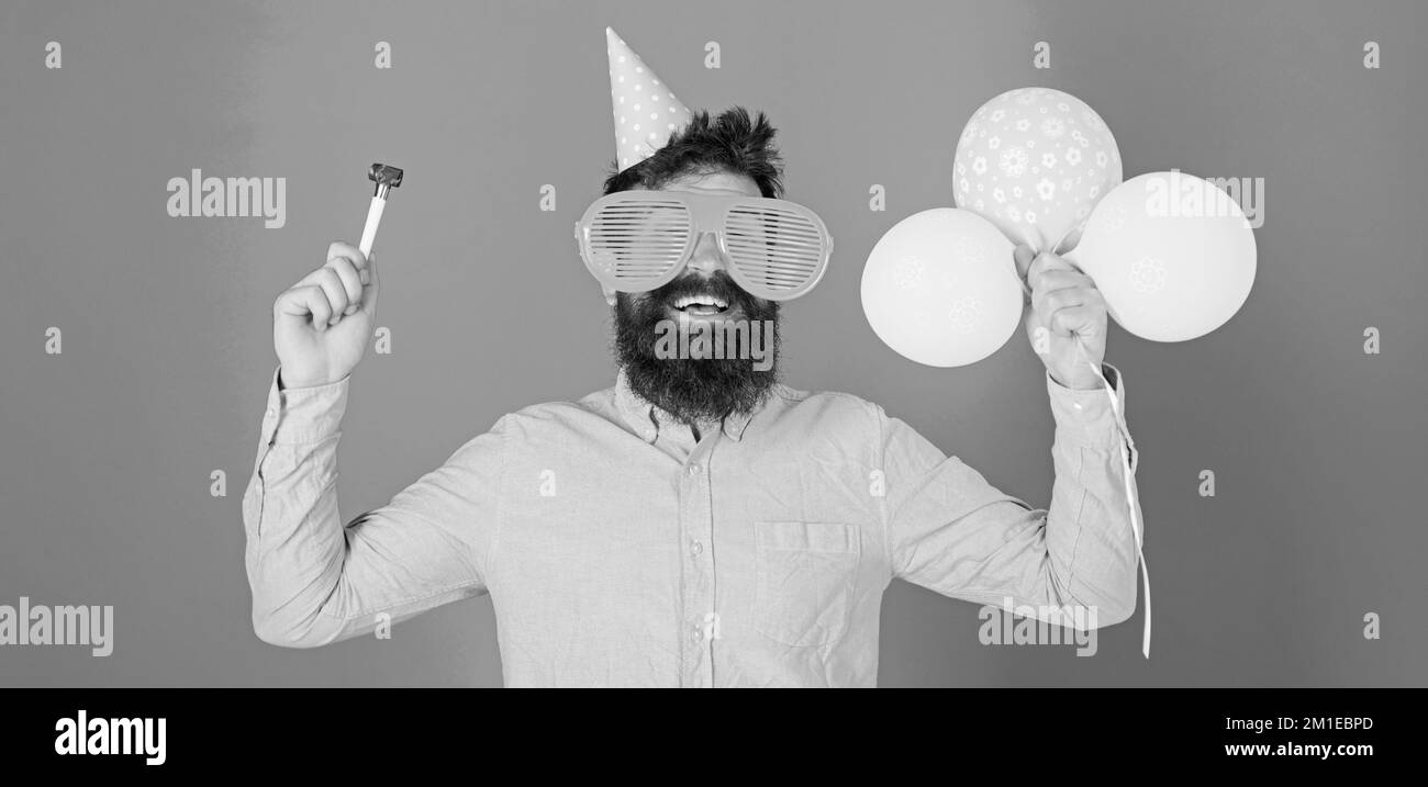 Waist up shot of good looking positive man with beard holding helium ...