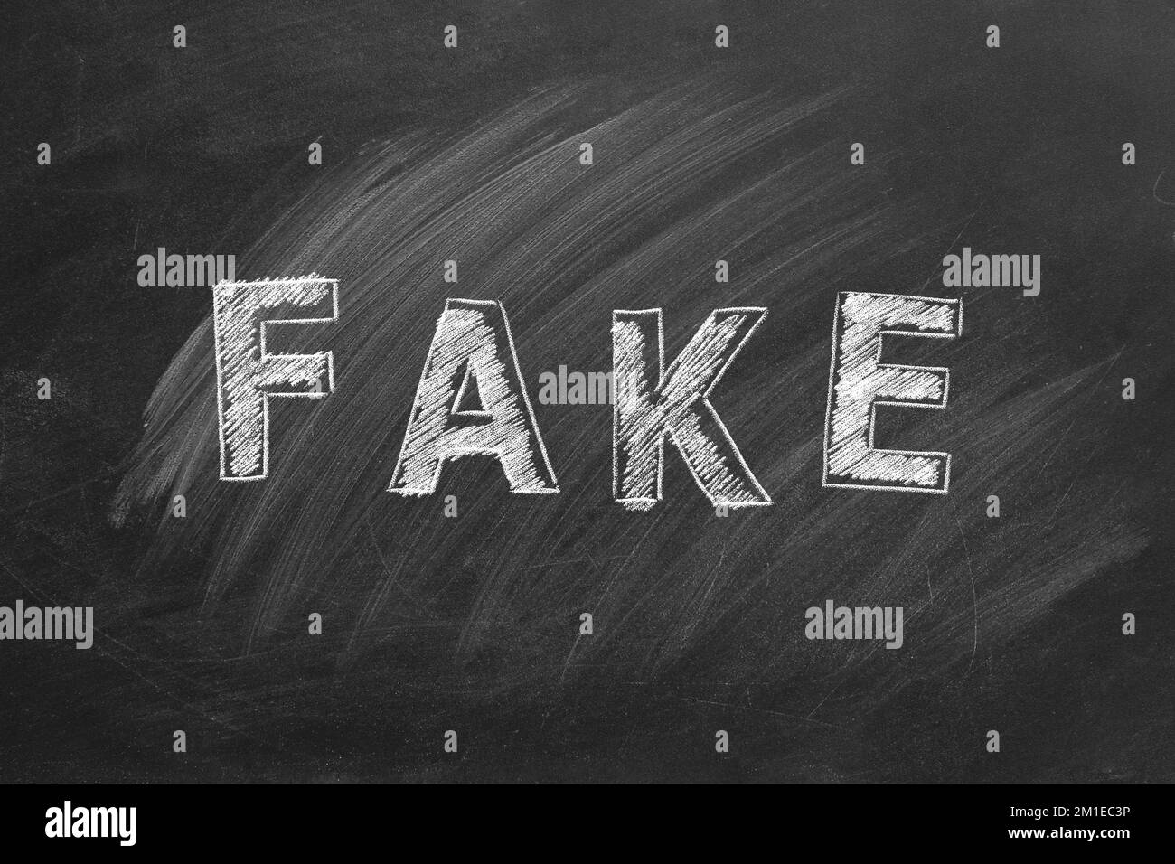 The word FAKE written in chalk on a blackboard. Information and ...