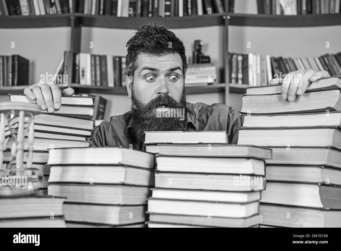 Teacher or student with beard sits at table with books, defocused. Man ...