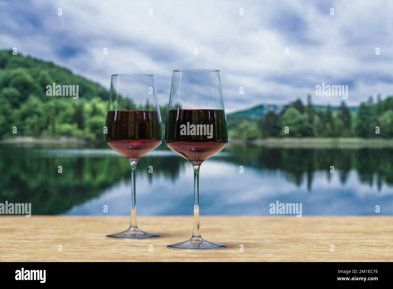 Two glasses of red wine with lake in a forest background Stock Photo ...