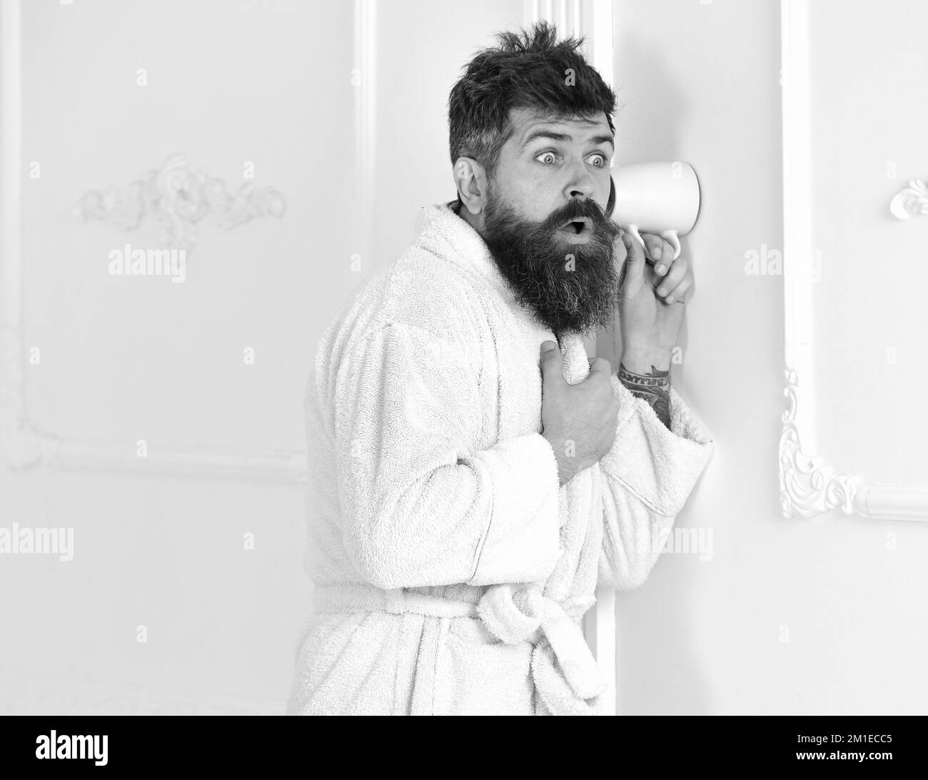 Man with beard and mustache eavesdrops using cup near wall. Hipster in ...