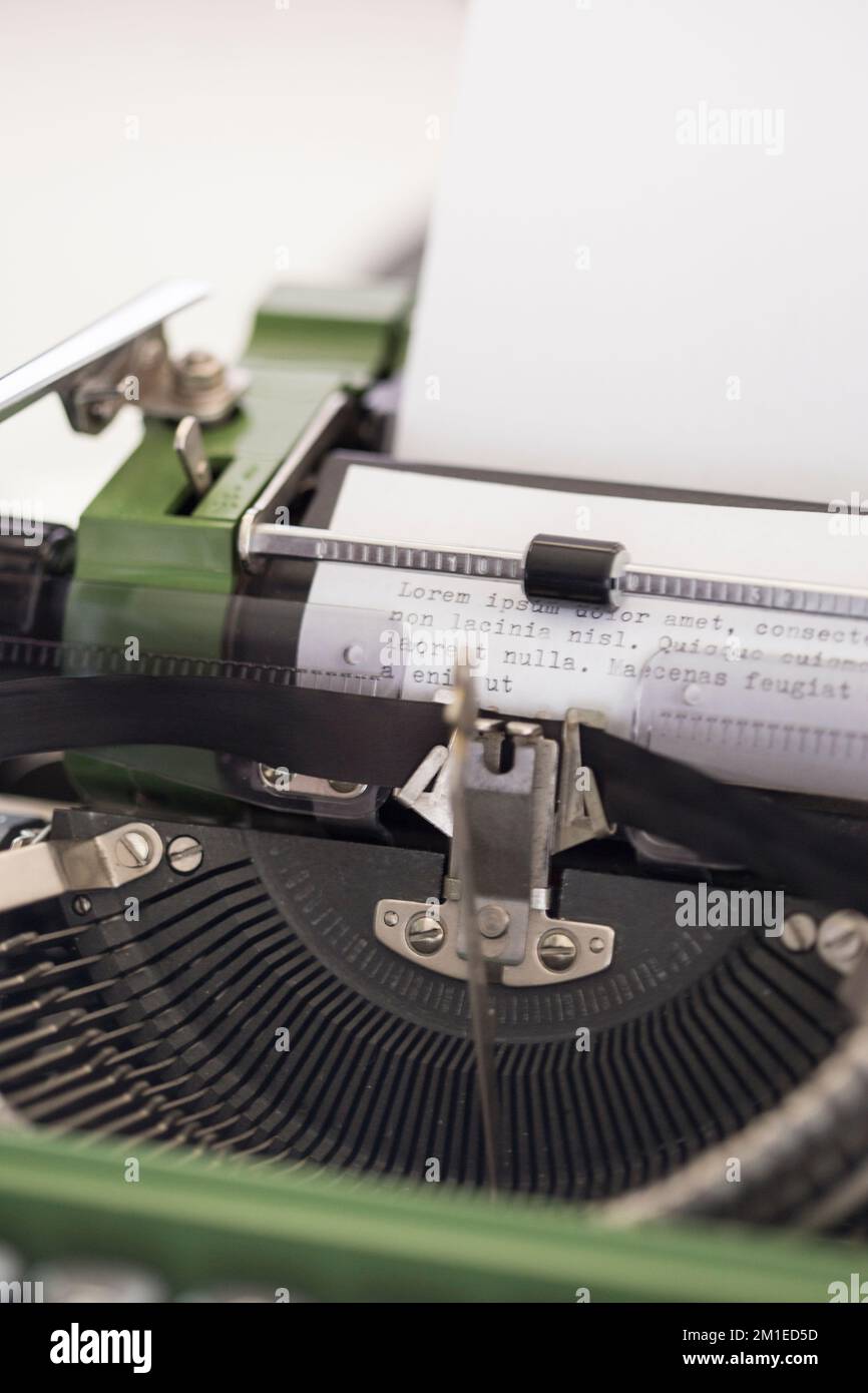 Vintage green typewriter machine with a sheet of paper and generic text ...