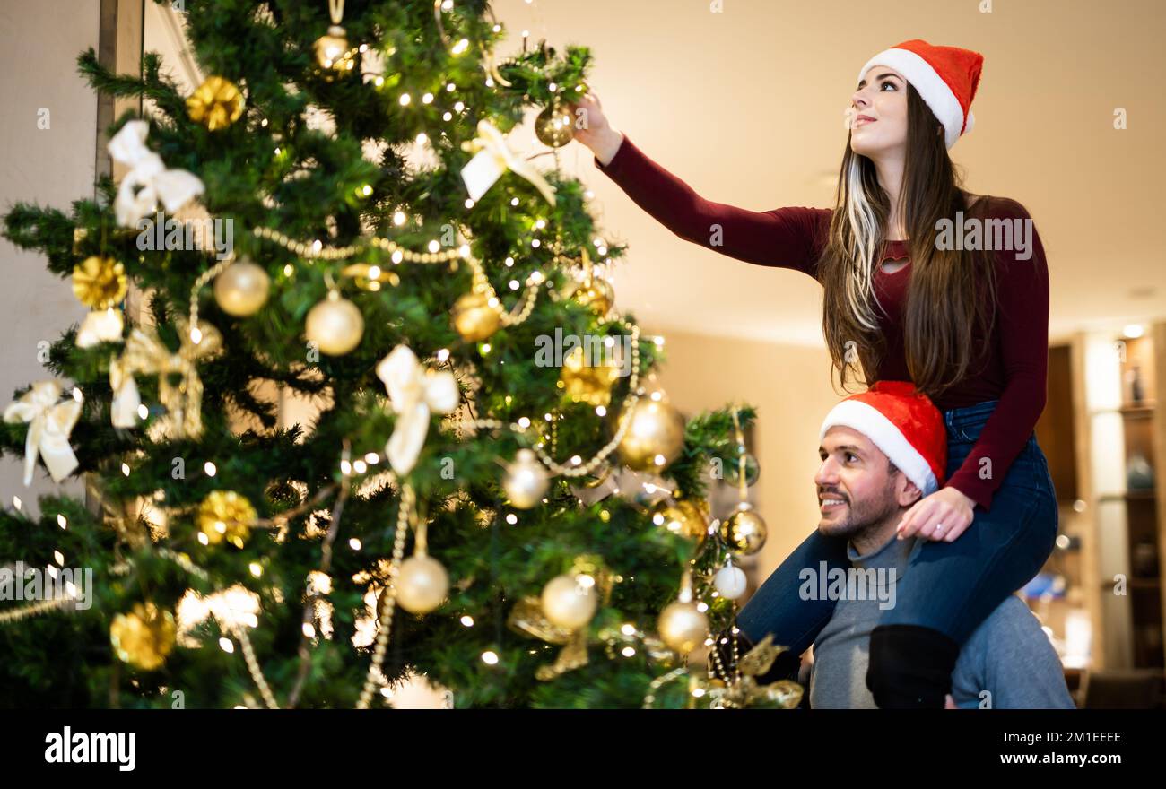Happy couple decorating a christmas tree together Stock Photo - Alamy