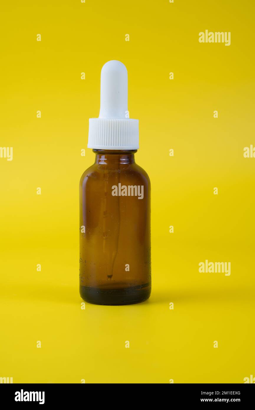 Medical brown glass dropper bottle empty isolated against a yellow ...