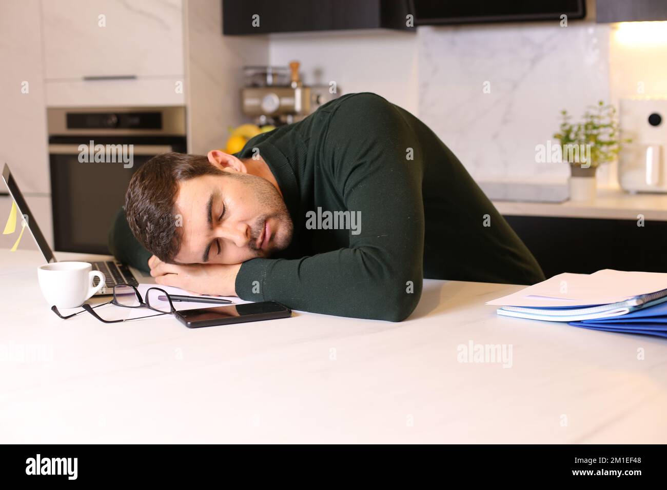 Man falling sleep while working remotely from his kitchen Stock Photo ...