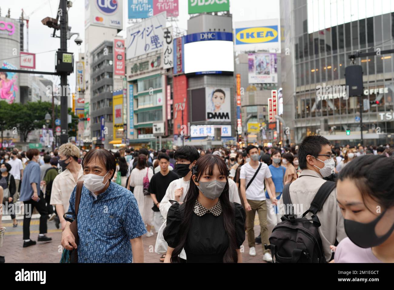 The huge crowd of people waring masks in Tokyo square in the daylight ...