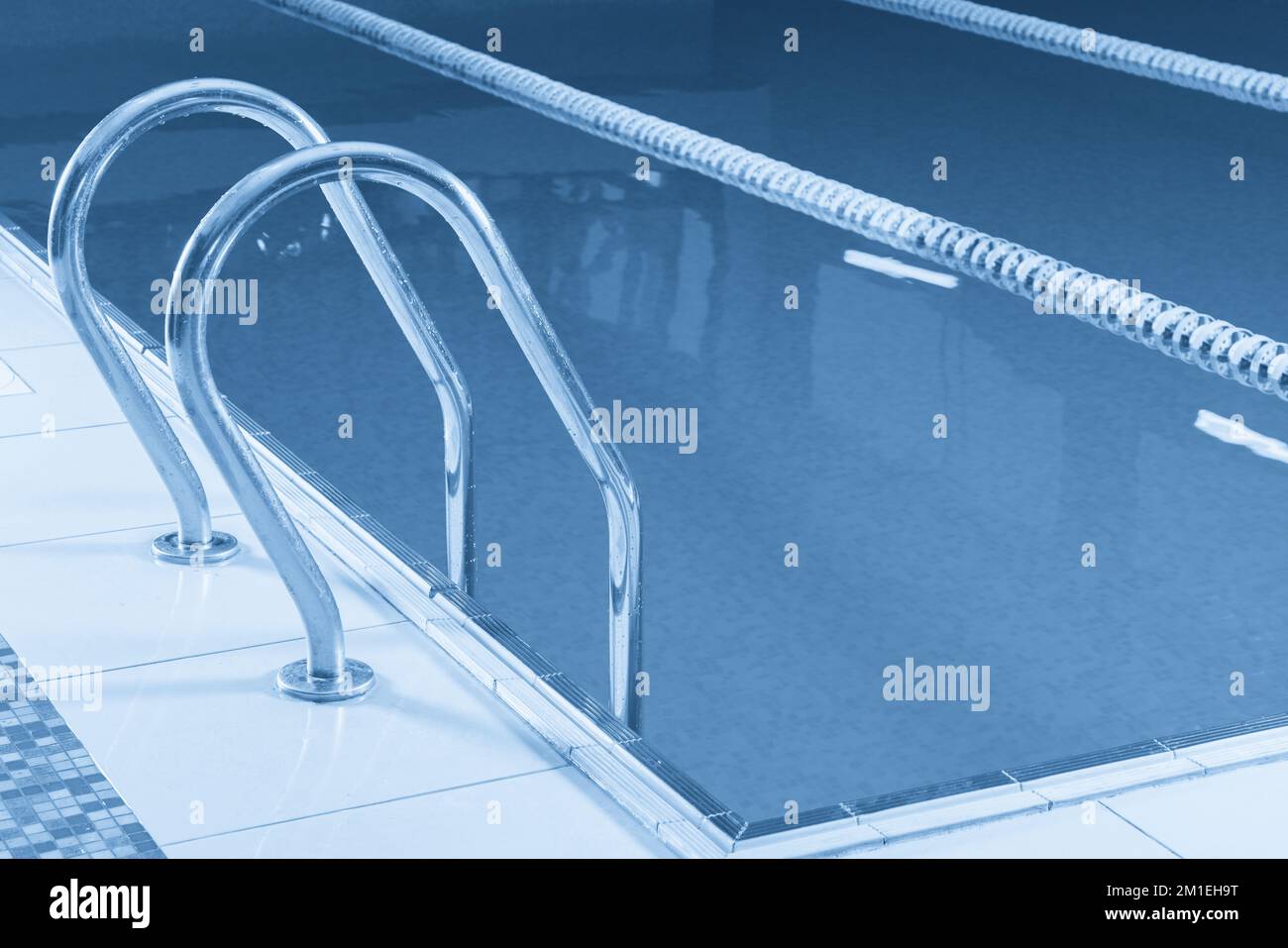 Empty indoor swimming pool with railing and steps in water Stock Photo ...
