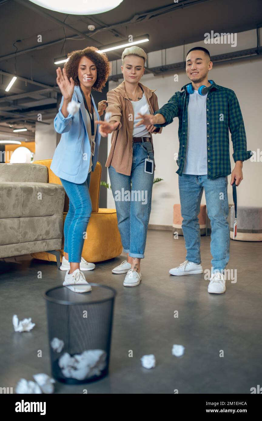 Serious female company employee and her cheerful colleagues throwing ...