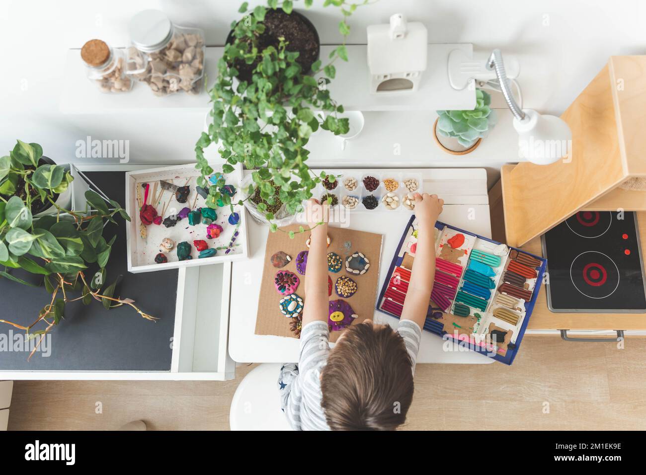 Baby boy creating plasticine diy figure with decorate dried beans ...