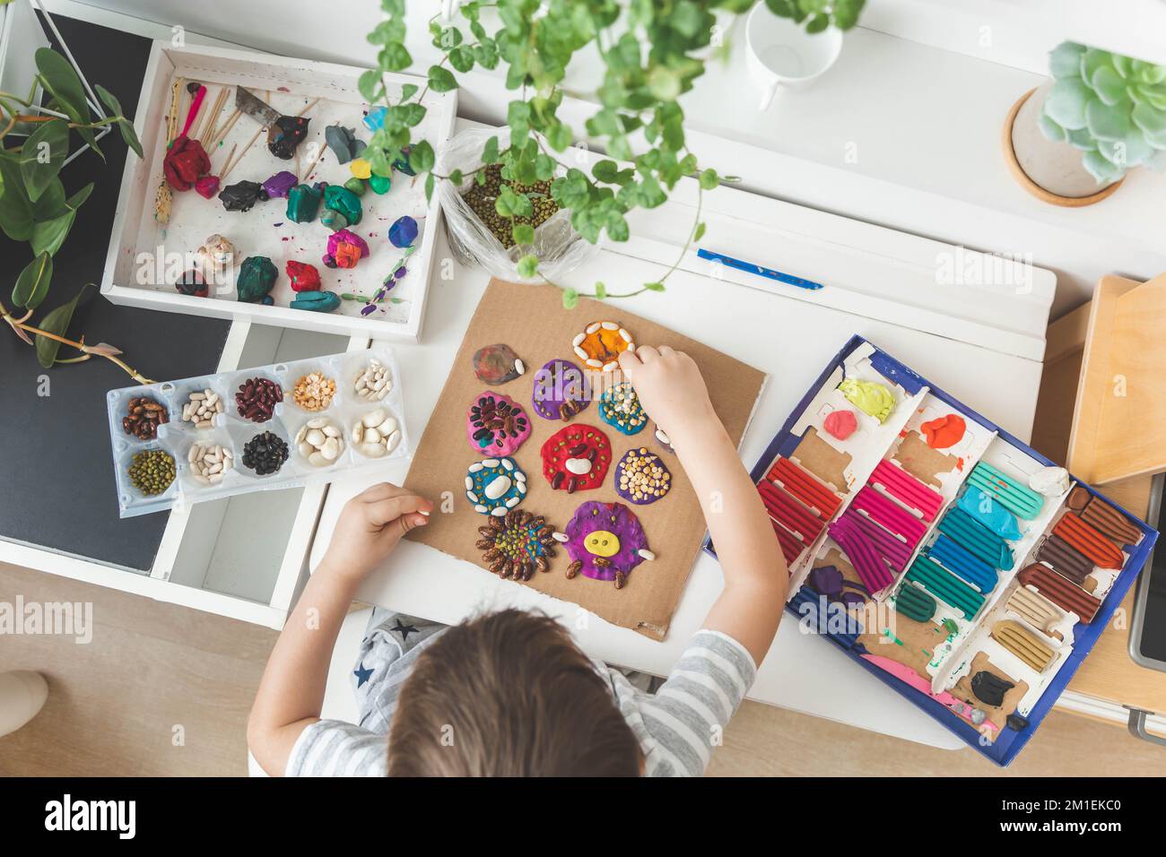 Baby boy creating plasticine diy figure with decorate dried beans ...