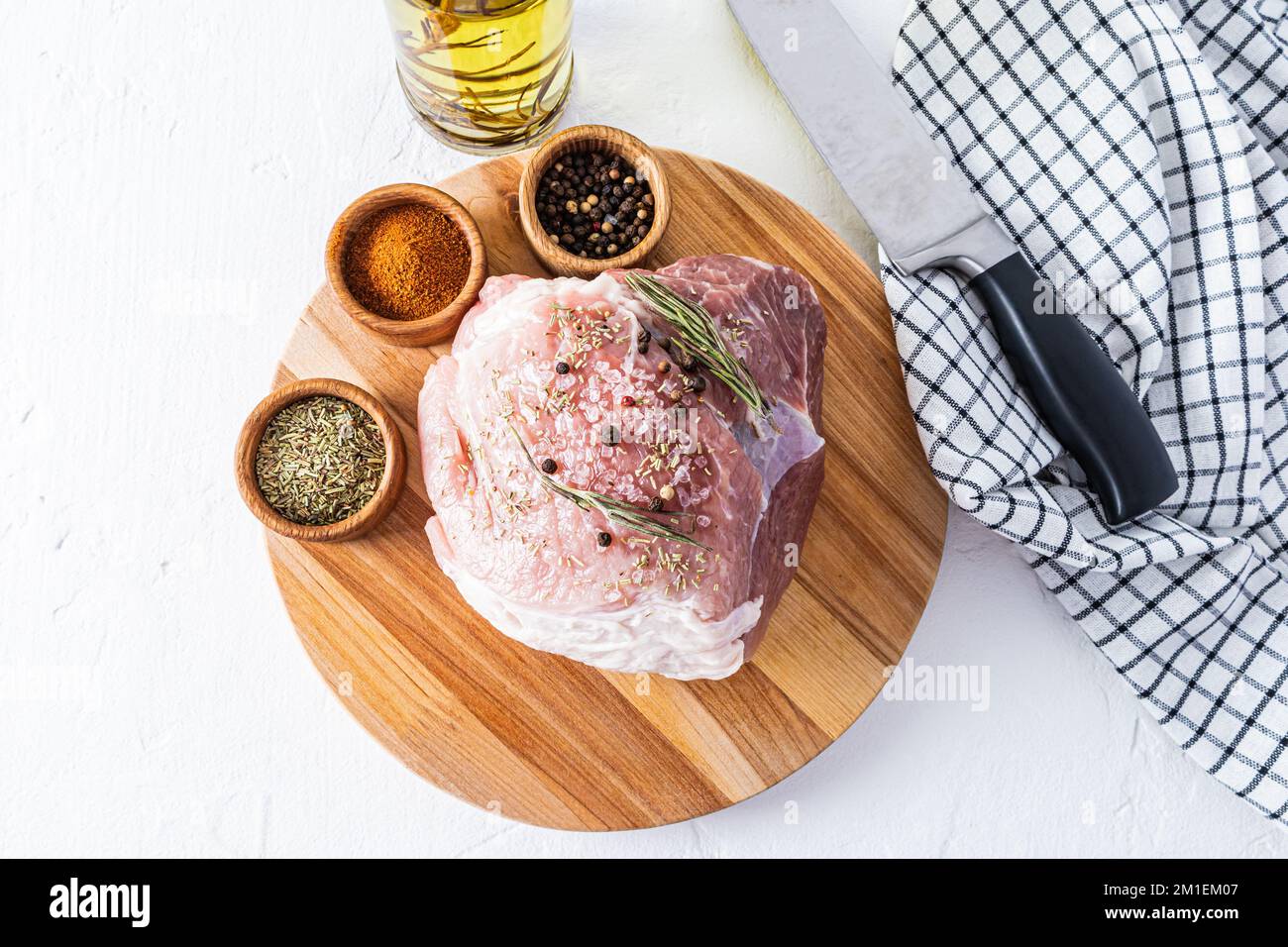 a large fresh piece of pork for baking lies on a round wooden board ...
