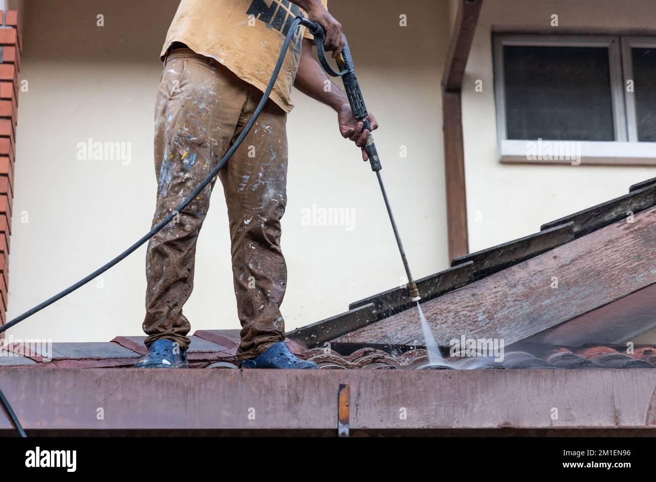 Worker using high pressure water jet spray gun to wash and clean dirt ...