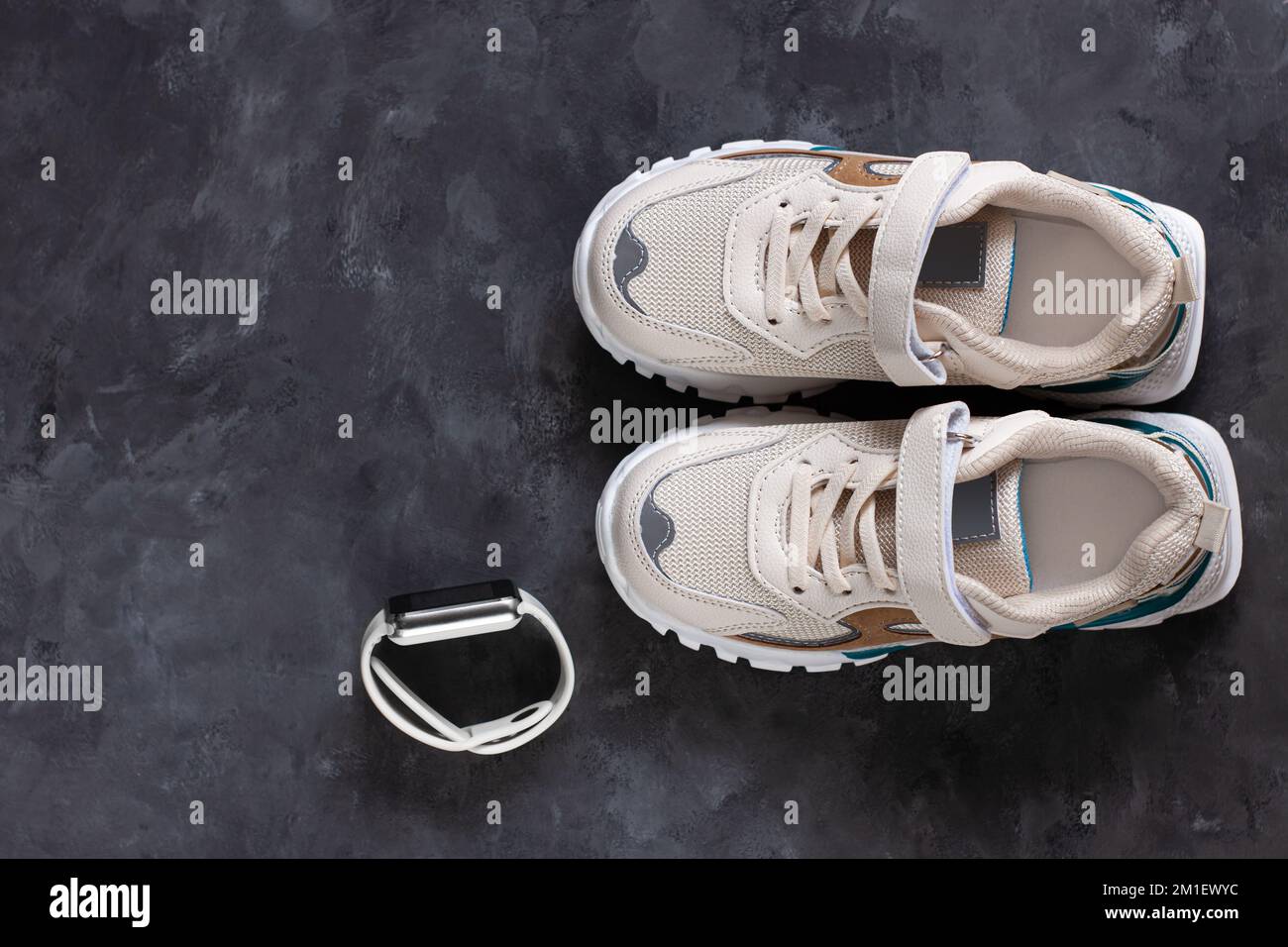 White sneakers and sports watch on a dark grey background flat lay in ...