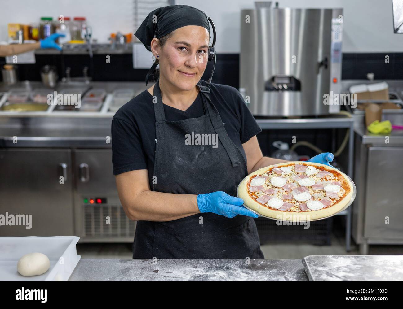Female chef with pizza in restaurant kitchen Stock Photo - Alamy