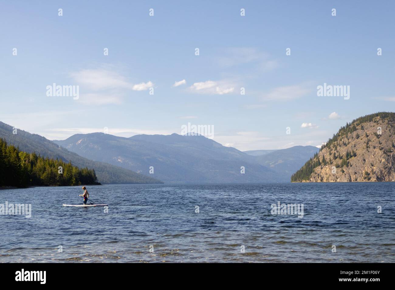 A paddle boarder on a lake with mountains in the background Stock Photo ...