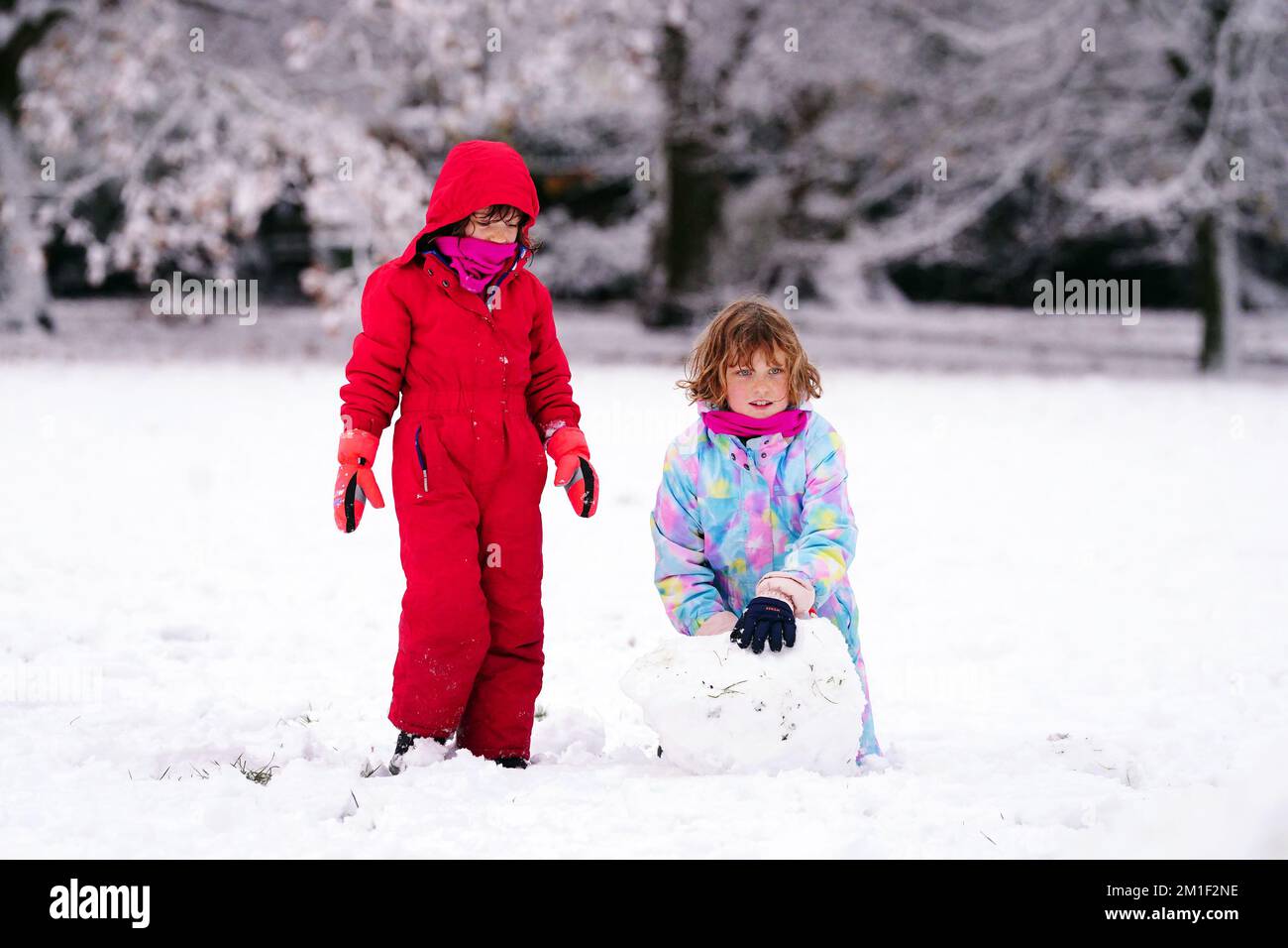Sisters Molly and Mia Wasilewicz make a giant snowball in the snow at ...